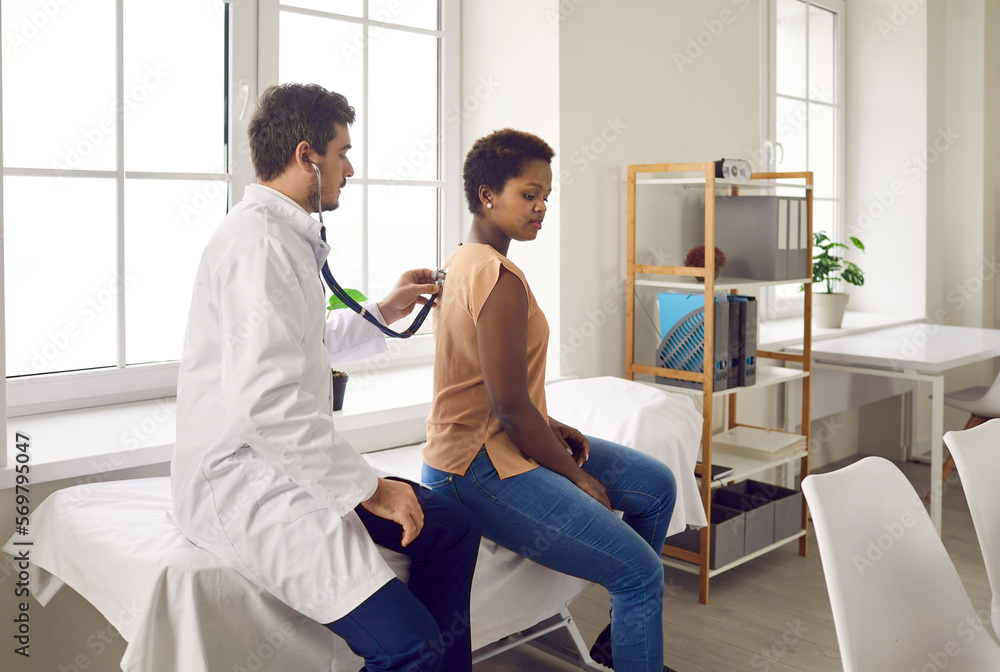 Young black woman seeing doctor for health checkup. Male physician at ...