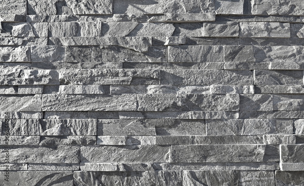 Stone cladding wall made of stacked rough bricks of light gray color ...
