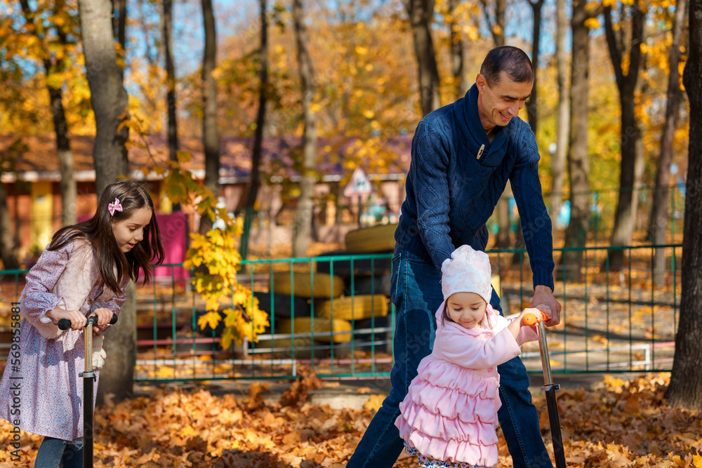 dad and children spend time together in the autumn city park, children ...