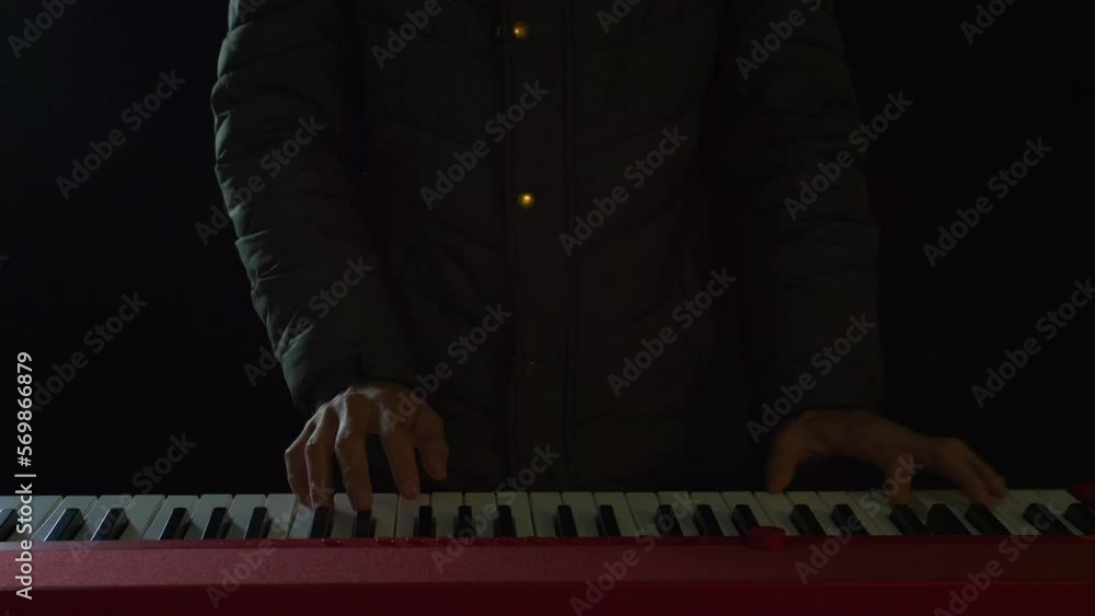 Close up front view of an elegantly dressed man playing the piano with ...