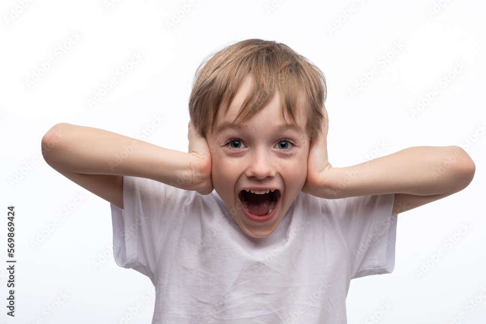A little boy in a white T-shirt stands on a white background, covers ...