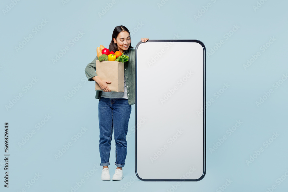 Full body young woman in casual clothes hold bag with food products ...