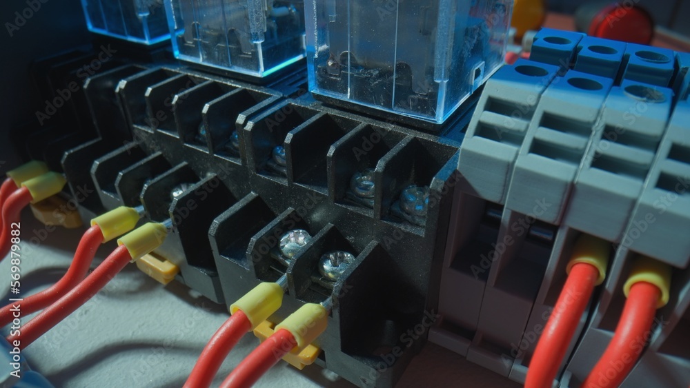Gray plastic electrical panel with many red wires, yellow bushing ...