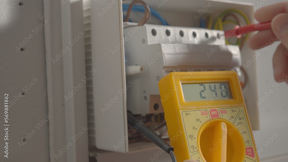 Work under voltage, electrician is checking serviceability of equipment ...