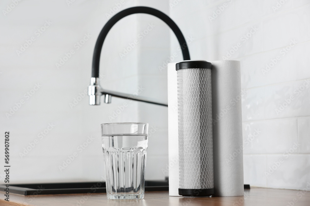 A glass of clean fresh water and set of filter cartridges on wooden ...