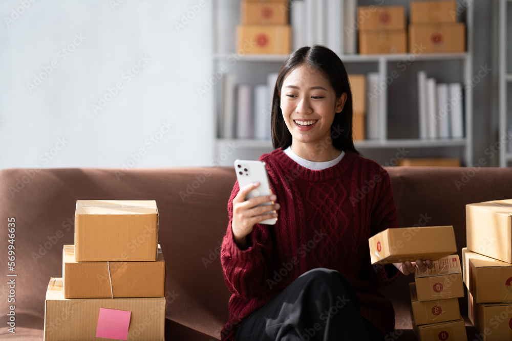 Online business owner woman answer phone chat with customers and write ...