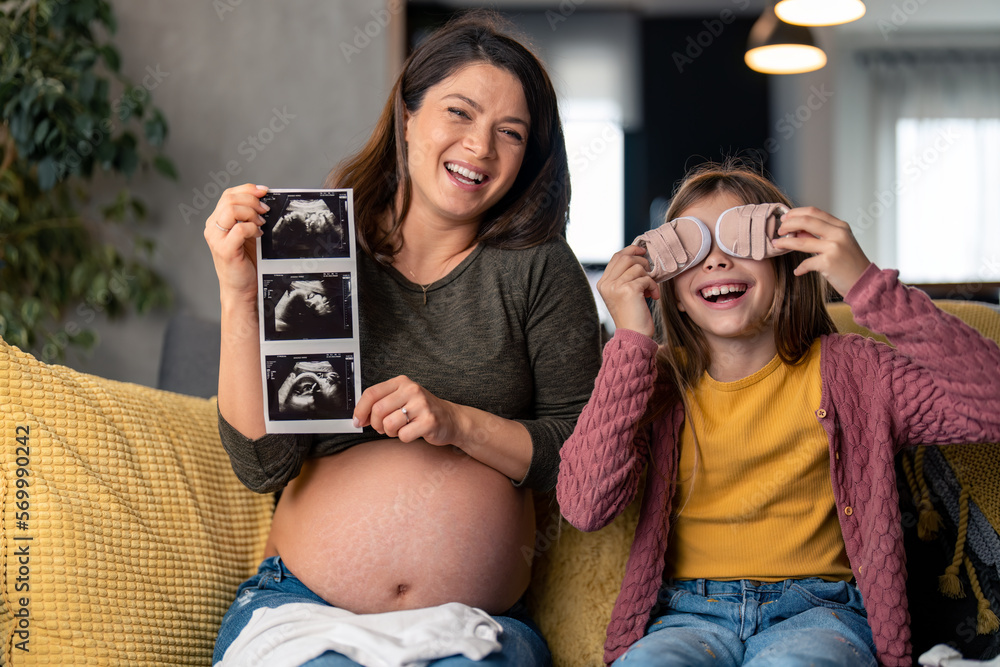 Young pregnant woman showing series of sonogram pictures of her second ...