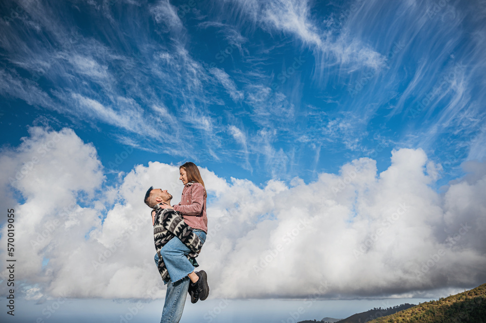 Couple in a stunning landscape, man holds the woman as she wraps her ...