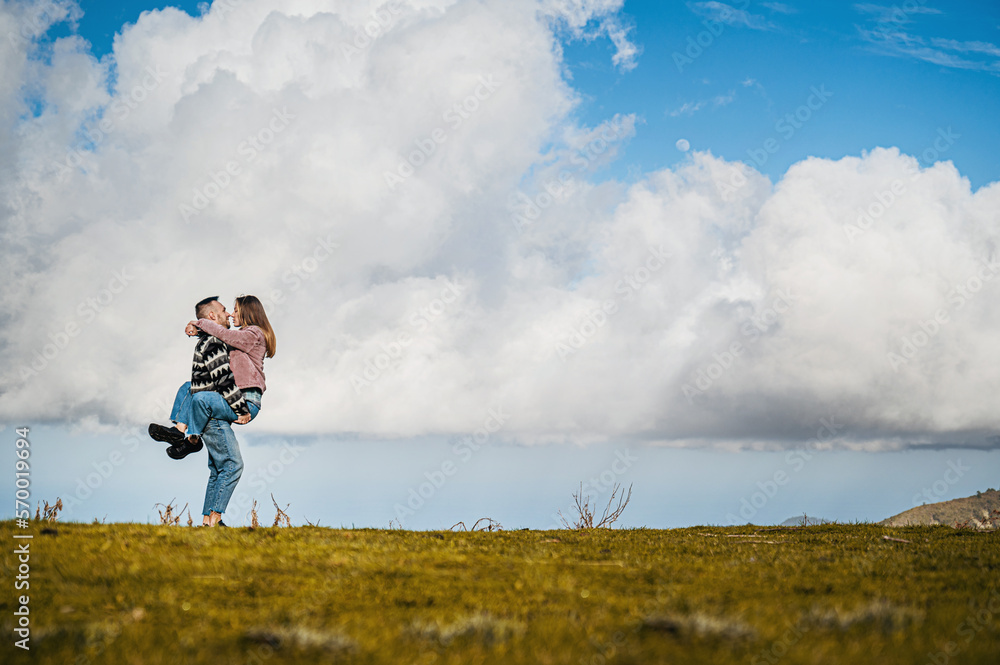 Couple in a stunning landscape, man holds the woman as she wraps her ...