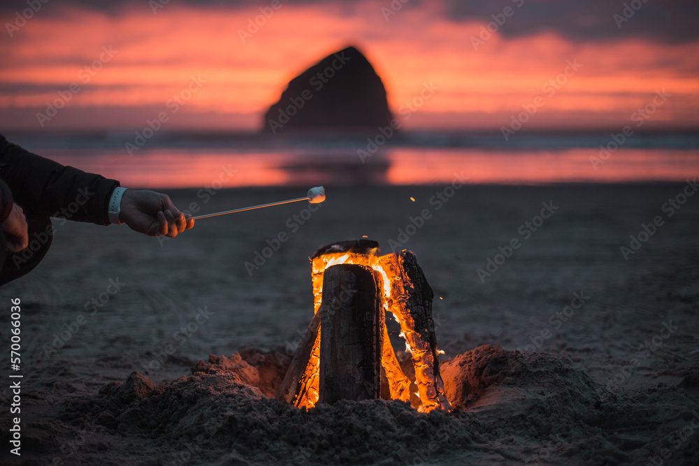 Man's hand with an marshmallow, Inviting campfire on Cape Kiwanda Beach ...