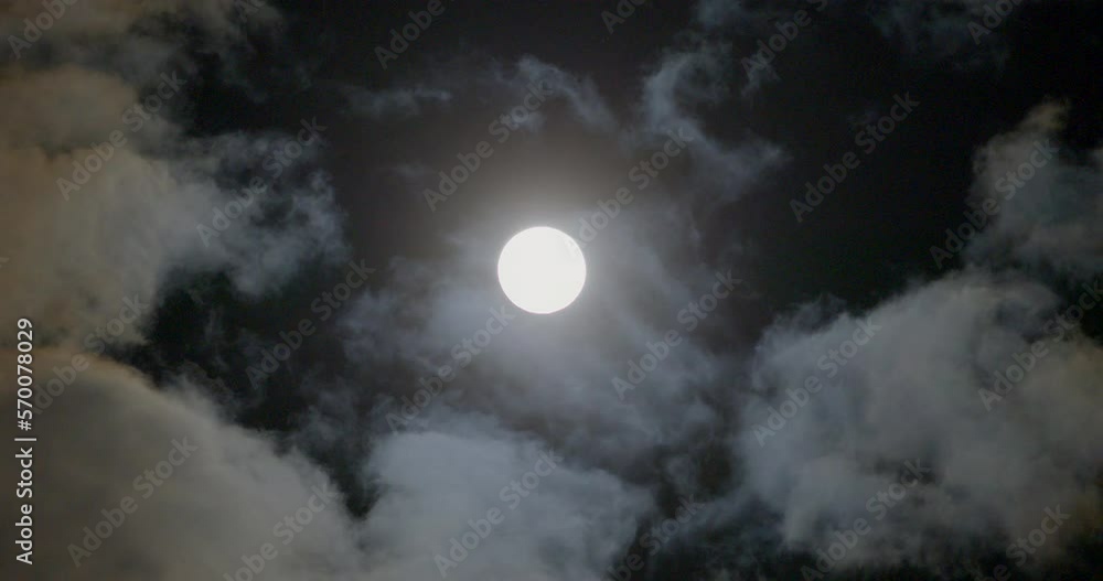 Rapid movement of clouds in the night sky, round moon white circle. The ...