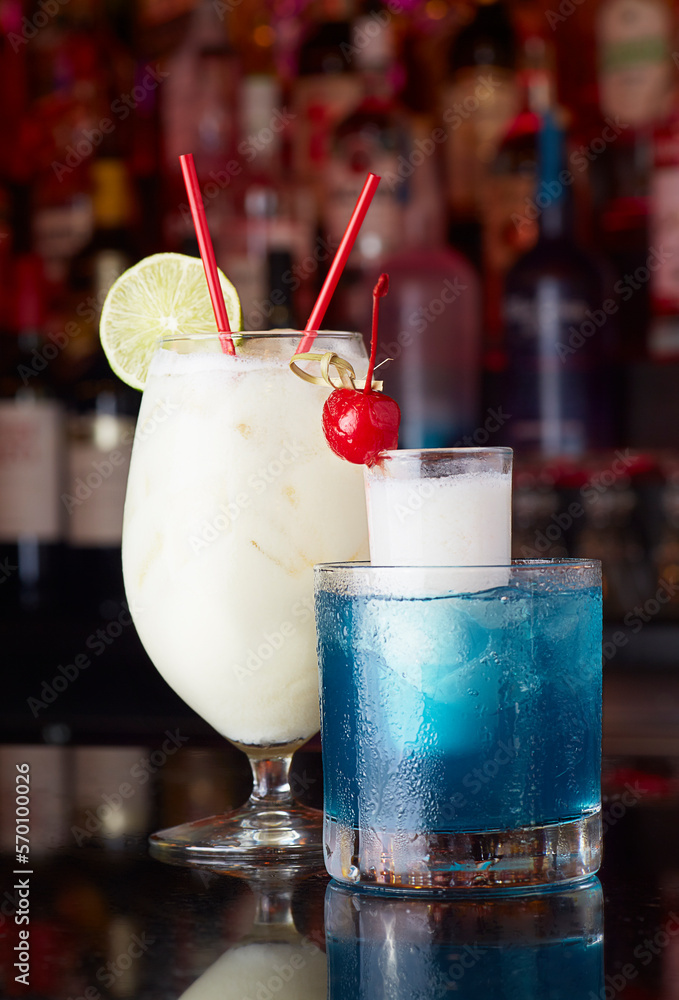Piña colada and blue curaçao cocktail drink in glasses on a bar with ...