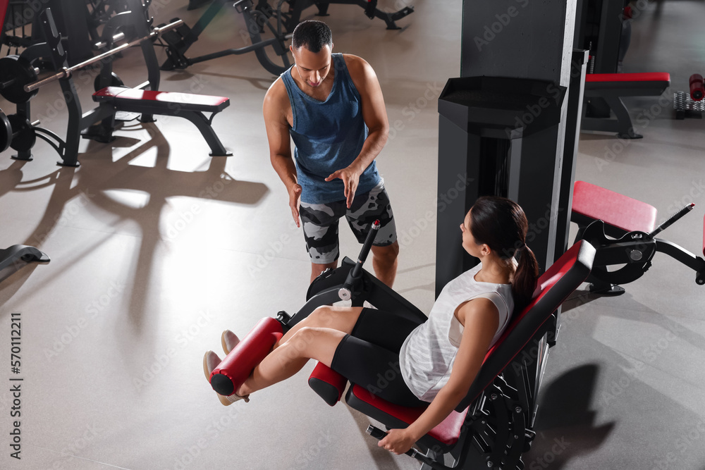 Trainer explaining woman how to do exercise properly in modern gym ...