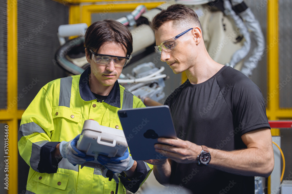 engineer team working program robot welding arm in automated factory ...
