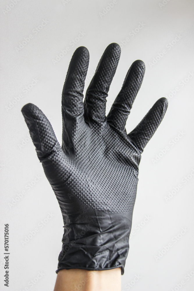 A hand in a black rubber glove on a white background. Personal ...