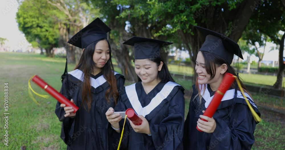 Asian students in graduation gowns with diplomas standing and ...