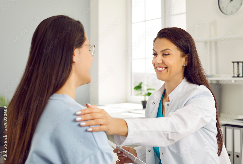 Friendly smiling female doctor holding woman's shoulder telling her ...