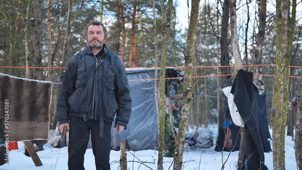 Foto de A homeless man poses in the woods in front of his hut. do Stock ...
