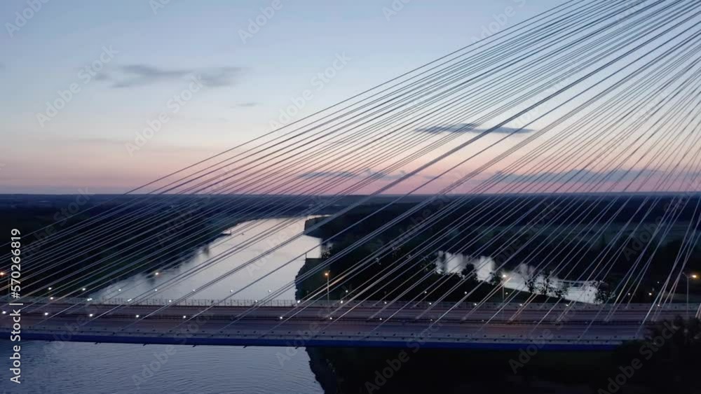 Drone video of big white cable-stayed bridge at dusk with cars moving ...