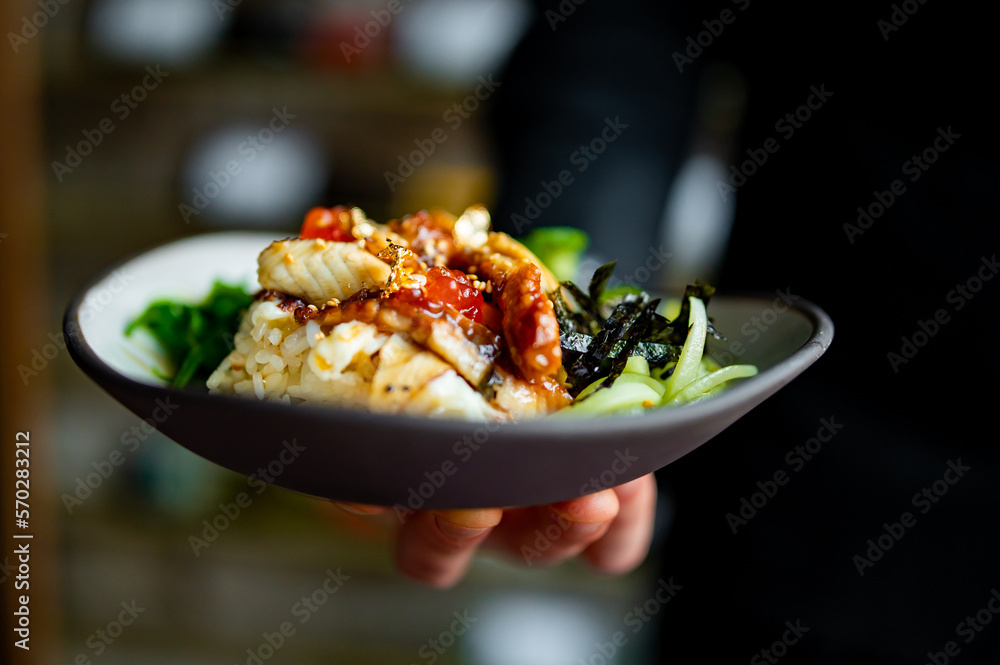 chef holding delicious donburi bowl with fish, rice and vegetables ...