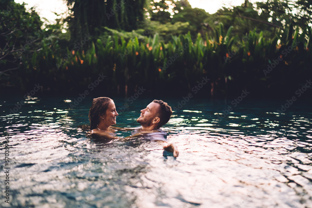 Cheerful Caucaisan couple in love bonding and cuddling while swimming ...