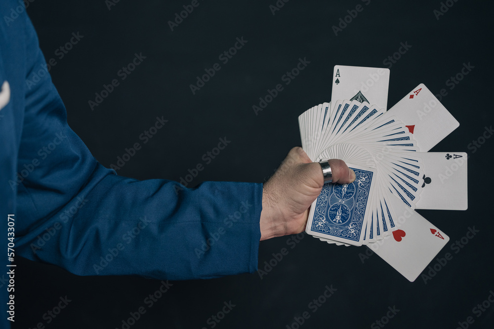Close-up image of a young magician's hand in the dark holding a fan ...