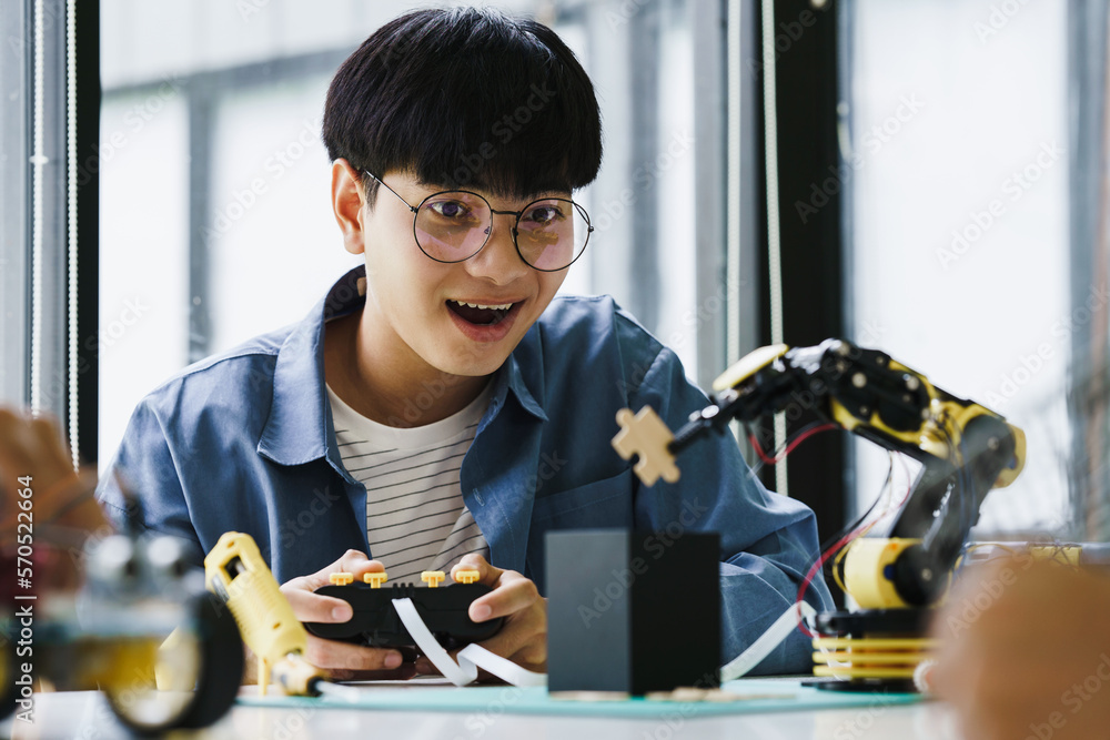 Asian teenager students doing or playing robot arm and robotic cars ...