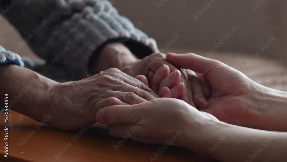 hands of adult son and elderly father shaking hands. son takes care of ...