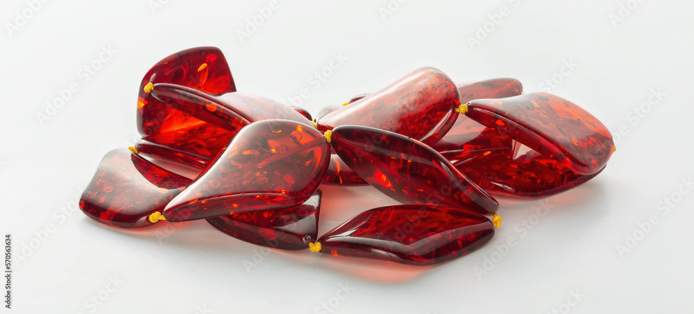Transparent polished beads of red amber on a white background. Sun ...