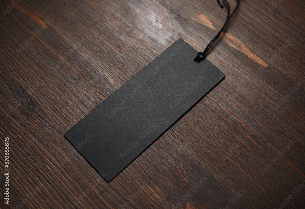 Blank black tag label with cord on wood table background. Mockup for ...