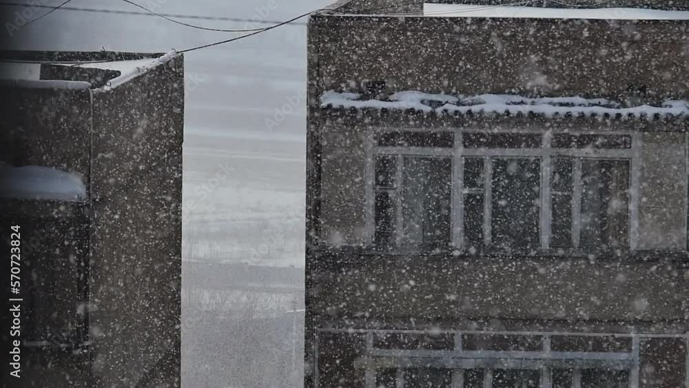 Intense snowfall hit the city of concrete gray houses with windows ...