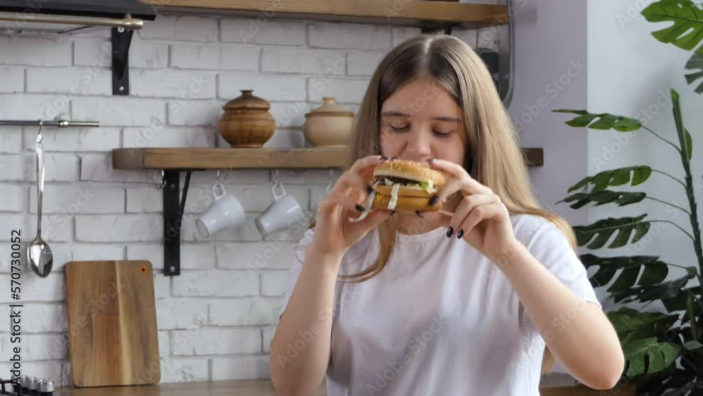 A young girl pushes a burger away and says the food is unhealthy with ...