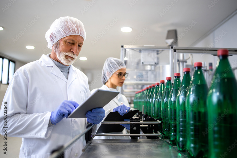 Concentrated quality control workers controlling production of bottled ...
