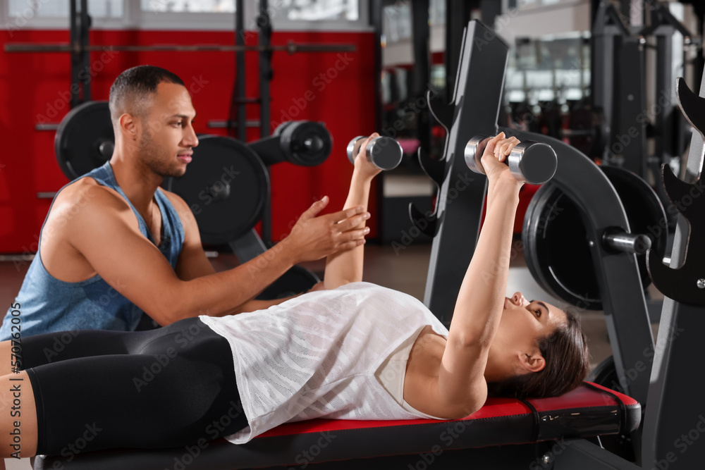 Trainer explaining woman how to do exercise properly in modern gym ...
