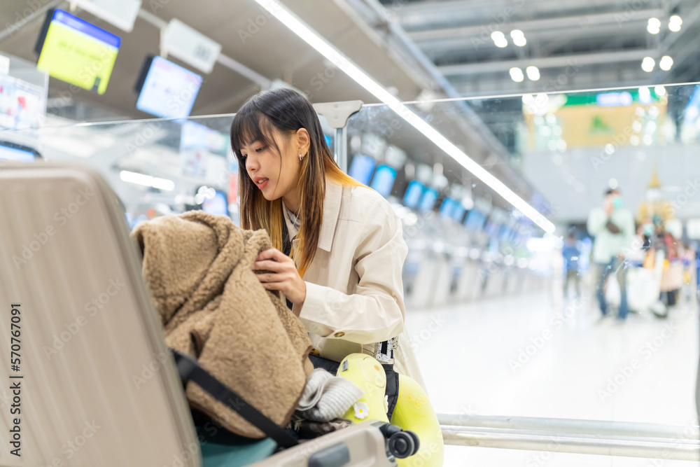 Attractive Asian woman repacking luggage before loading at check in ...