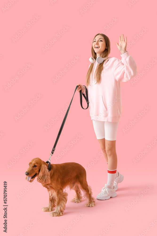 Young woman in headphones with cute cocker spaniel walking on pink ...