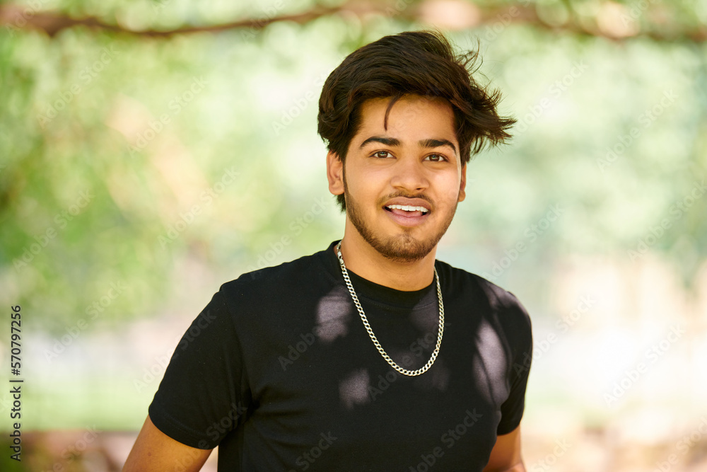 Smiling young indian man candid portrait in black t shirt and silver ...