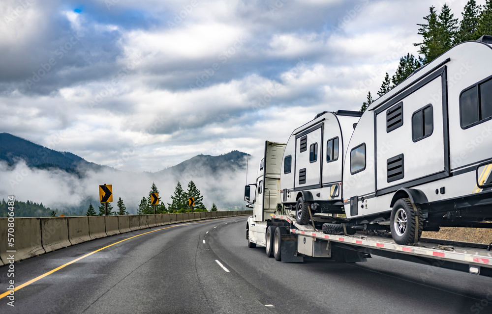 Long haul high cab white big rig semi truck transporting campers trucks ...