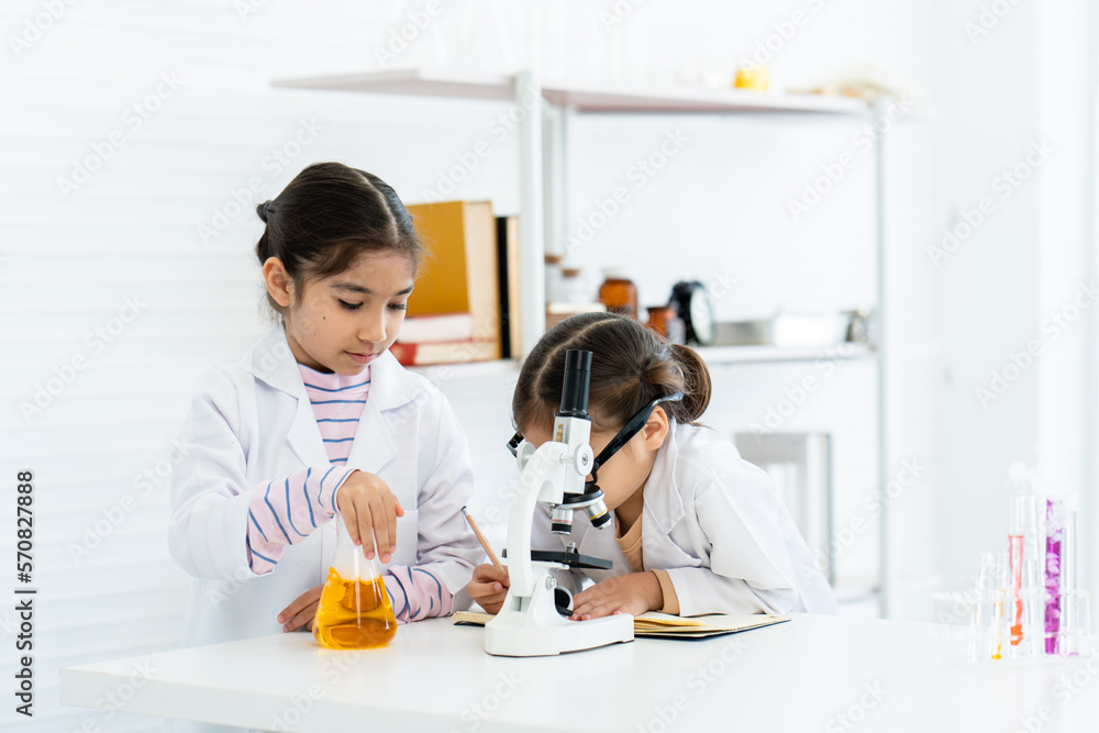 Two Arab schoolgirls are having fun learning science by practicing with ...