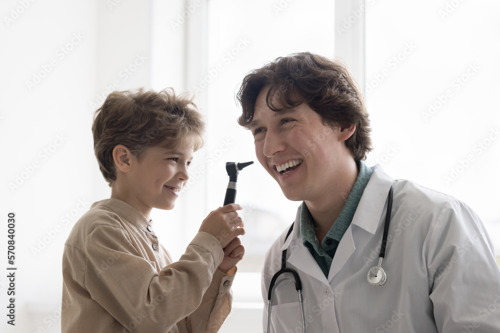 Joyful patient boy playing game with medical tool, pretending to check ...