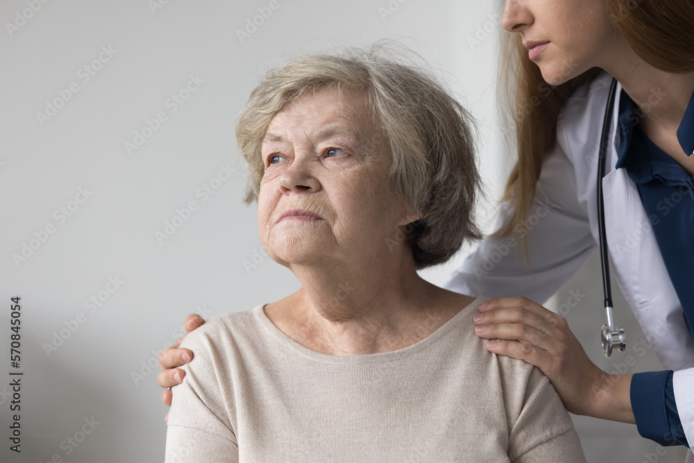 Thoughtful sad older patient woman sitting near doctor, getting comfort ...
