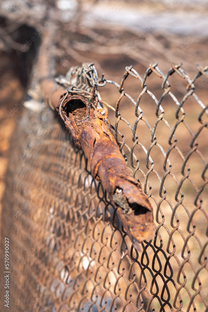 Close up of a rusty weathered metal chain link fence top pipe that is ...