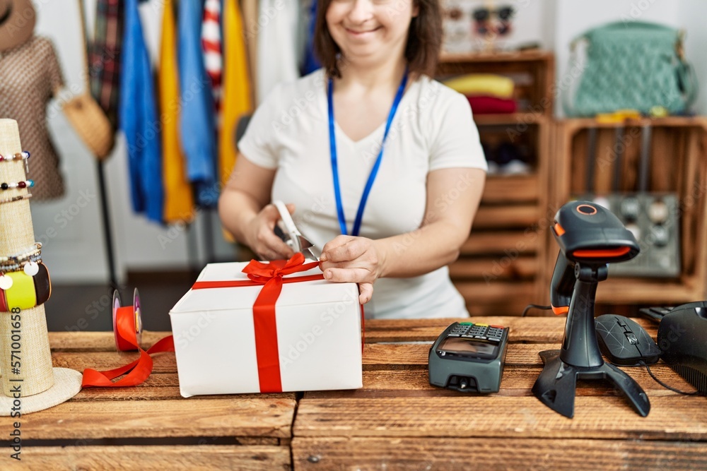 Brunette woman with down syndrome working as shop assistant wrapping ...