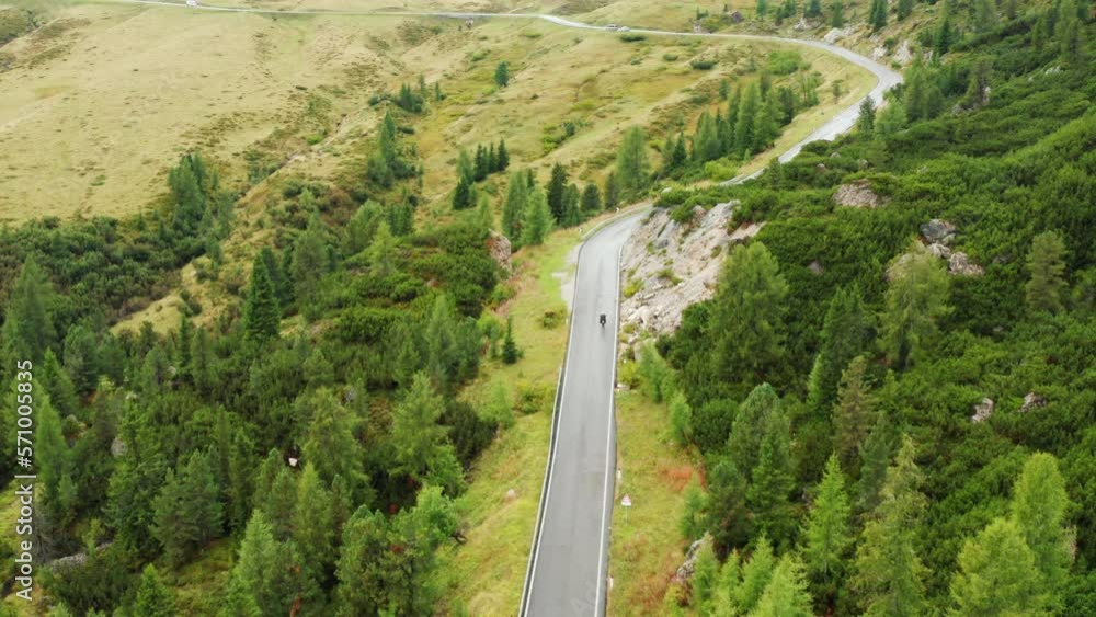 Tourist rides bike along Snake Road across high mountain valley ...