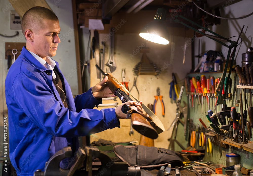 Gunsmith examines an automatic rifle before being repaired in a weapons ...
