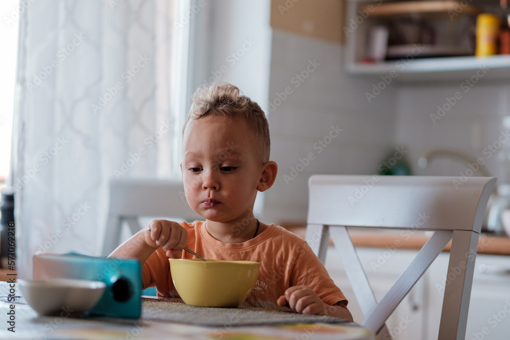 Little boy child toddler watching cartoons on mobile phone while eating ...