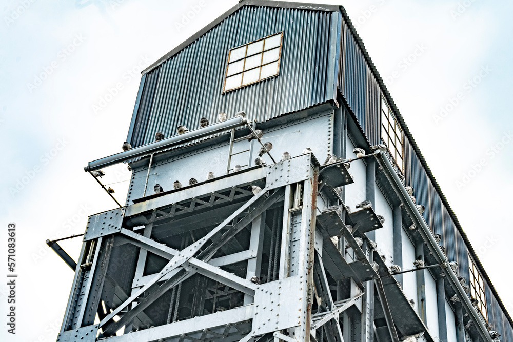 Gantry building under a cloudy sky with pigeons Stock Photo | Adobe Stock