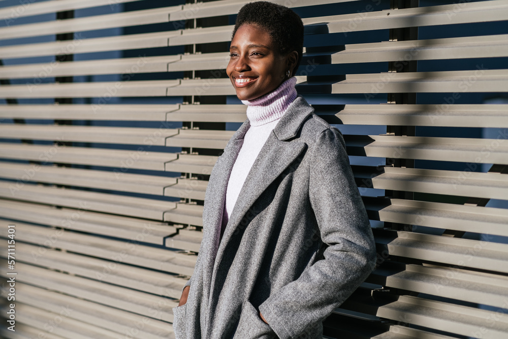 Positive black woman in stylish sweater and coat holding hands in ...