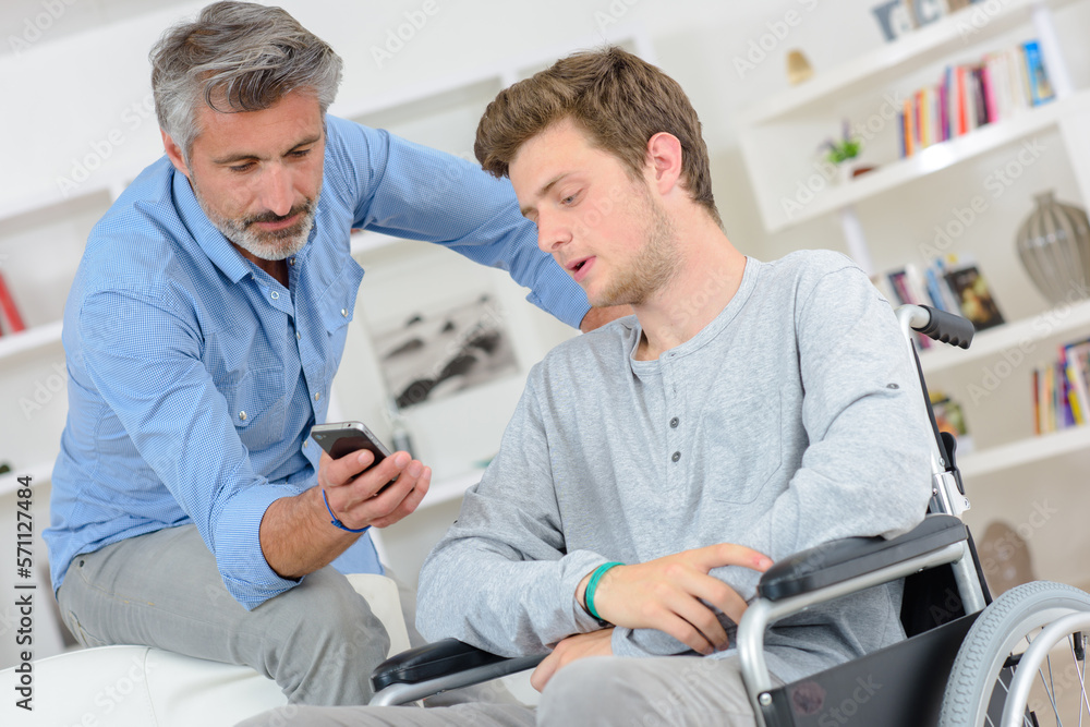 man showing an sms on a young boy on the wheelchair Stock Photo | Adobe ...