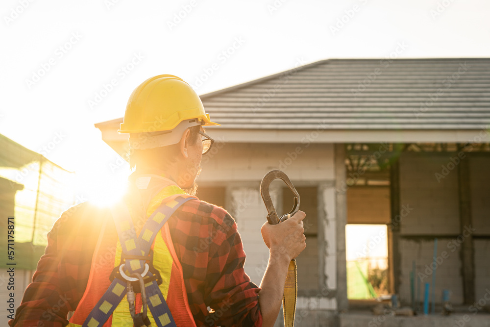 Construction worker wearing safety harness and safety line working on scaffolding at new house ...